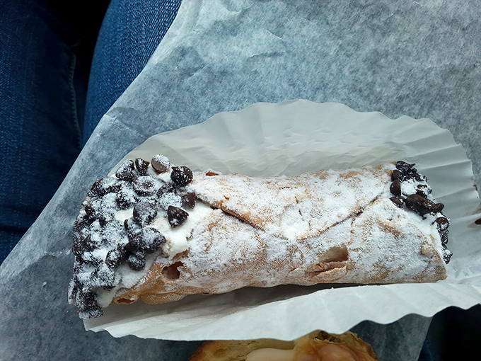 This cannoli isn't just a pastry—it's an edible love letter from Italy, dusted with powdered sugar and chocolate chips.