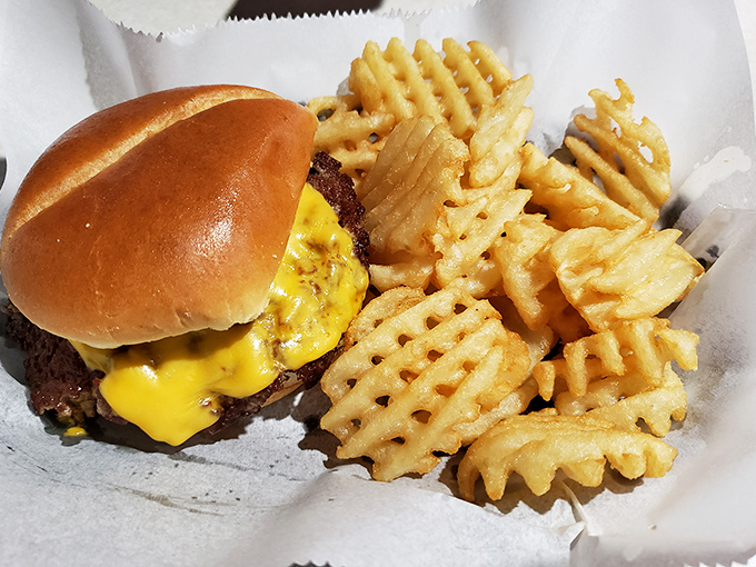 A proper burger and waffle fries—the kind of honest-to-goodness plate that reminds you why simple food done right beats fancy cuisine any day.