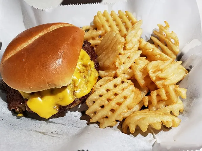 A proper burger and waffle fries—the kind of honest-to-goodness plate that reminds you why simple food done right beats fancy cuisine any day.