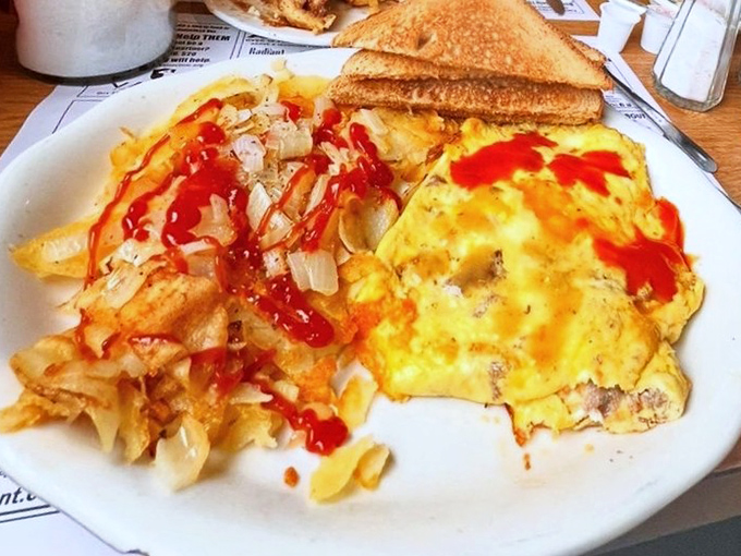 This omelet, draped in ketchup like a red carpet for your taste buds, proves that sometimes the simplest additions create breakfast masterpieces.