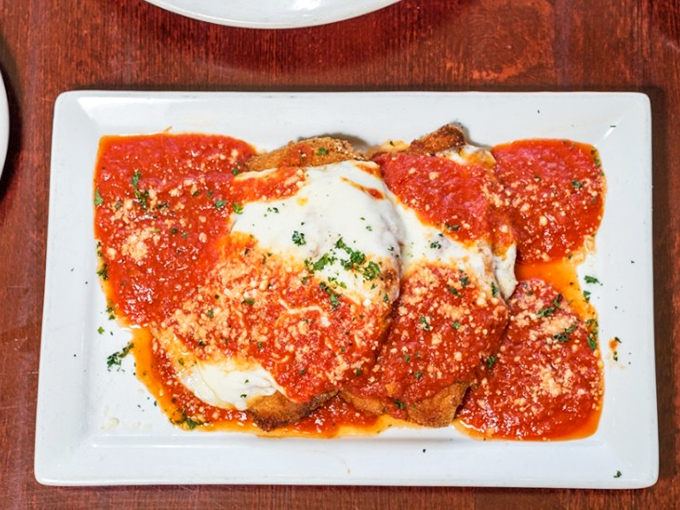 Chicken Parmigiana that doesn't just sit on the plate—it lounges luxuriously under a blanket of melted cheese and marinara like it owns the place. 