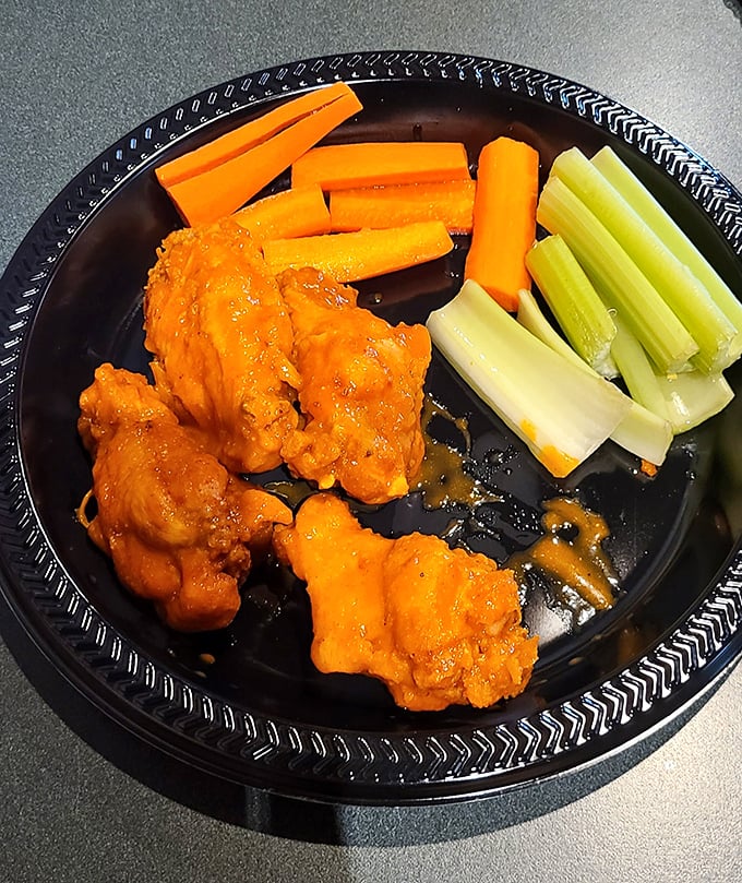 These buffalo wings aren't just orange—they're practically glowing with flavor potential, standing at attention next to their cooling vegetable companions.