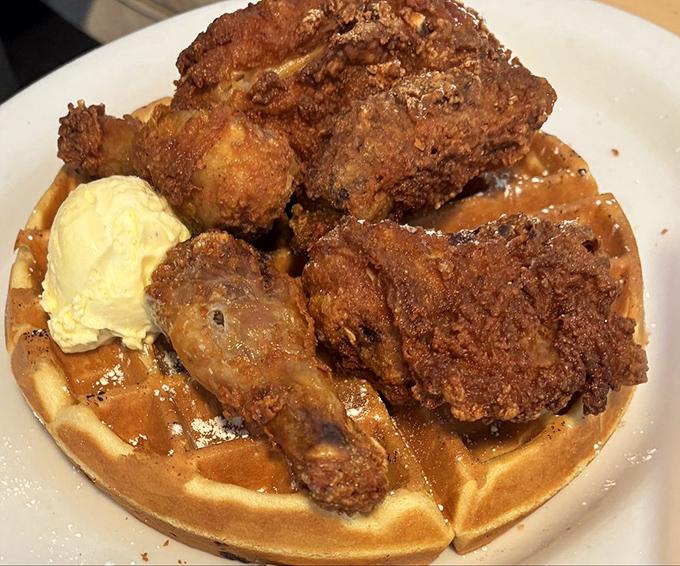 Chicken and waffles that breaks the laws of physics—impossibly crispy chicken atop a fluffy waffle. The scoop of butter melts with cinematic timing.
