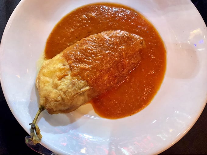 A chile relleno that's been given the royal treatment—egg-battered, cheese-crowned, and swimming in a sauce that's been simmering since sunrise.