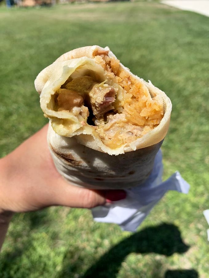 The Chile Verde burrito, enjoyed al fresco—proof that sometimes the best dining room is wherever you happen to be when hunger strikes.