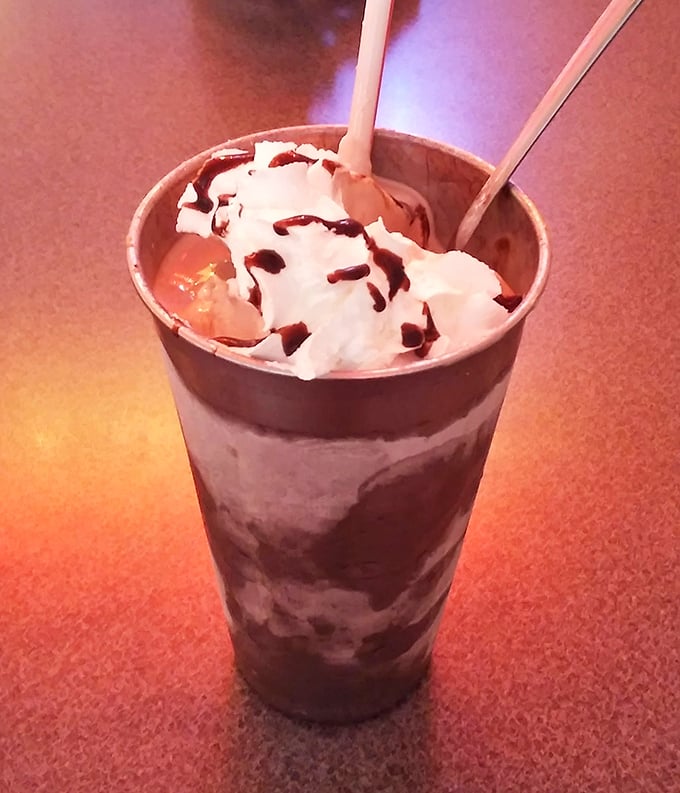 The chocolate milkshake arrives like a dessert skyscraper—thick enough to require serious straw commitment, topped with a cloud of whipped cream that defies gravity.