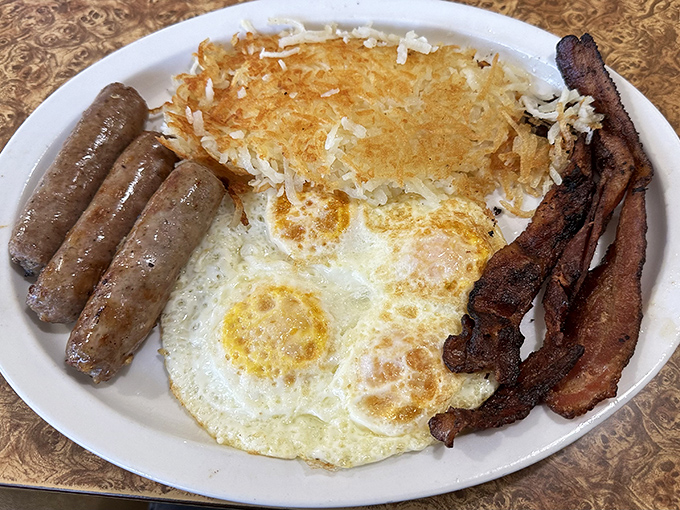 The holy trinity of breakfast: perfectly cooked eggs, crispy bacon, and sausage links that snap when you bite them. Add hash browns and you've got religion.