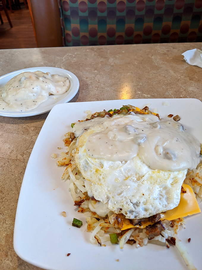 Behold: the country skillet with eggs and gravy—where breakfast meets architecture. This towering creation makes skyscrapers jealous with its perfect structural integrity.