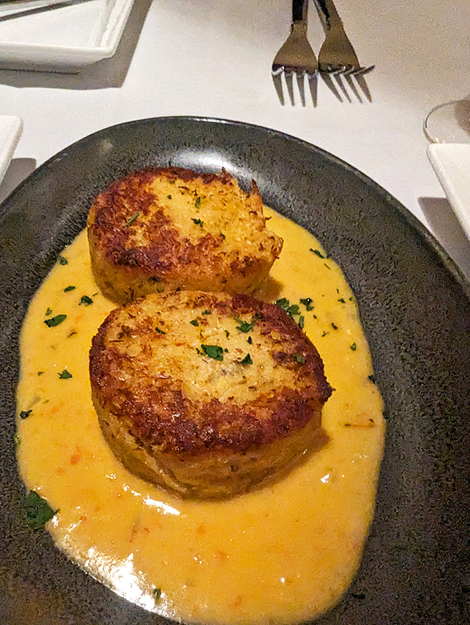 These golden crab cakes swimming in sunshine-colored sauce aren't just appetizers—they're the opening act that threatens to upstage the headliner.