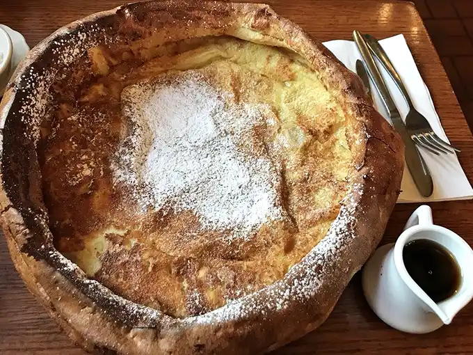 The Dutch Baby arrives like a golden crater from breakfast outer space, dusted with powdered sugar and ready for its lemon squeeze.