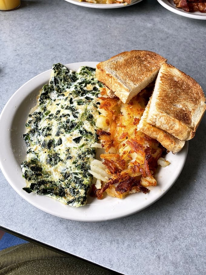 This spinach omelet isn't just healthy—it's a masterpiece of green and gold, paired with hash browns so perfectly crispy they deserve their own fan club.