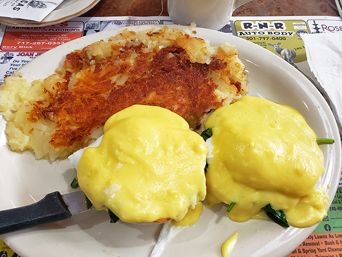 Eggs Benedict done right—velvety hollandaise cascading over perfectly poached eggs with hash browns crisped to golden-brown perfection.