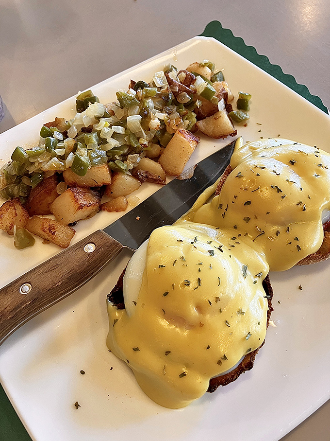 Eggs Benedict done right—hollandaise cascading down like a golden waterfall, with home fries that deserve their own fan club.
