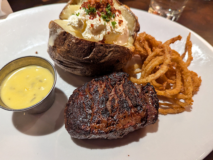 A perfectly seared filet mignon with a loaded baked potato and crispy onion straws—the holy trinity of steakhouse perfection.