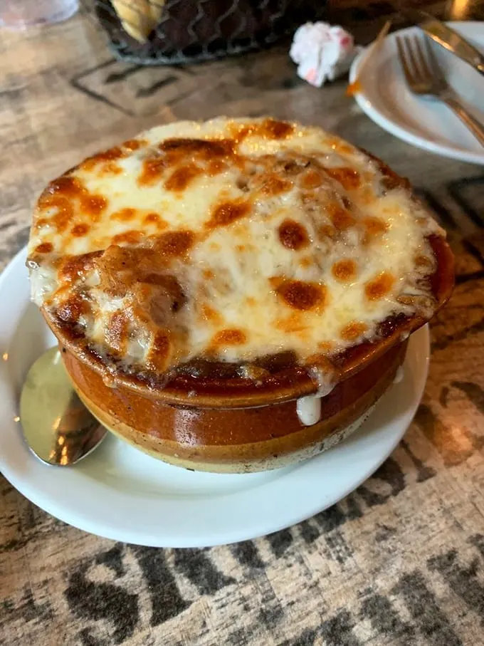 This French onion soup isn't just topped with cheese—it's wearing a magnificent golden crown that demands a moment of silence.