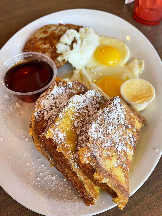 French toast that's dressed for success—golden, crispy edges giving way to custardy centers. The powdered sugar snowfall is just the beginning of this breakfast journey.