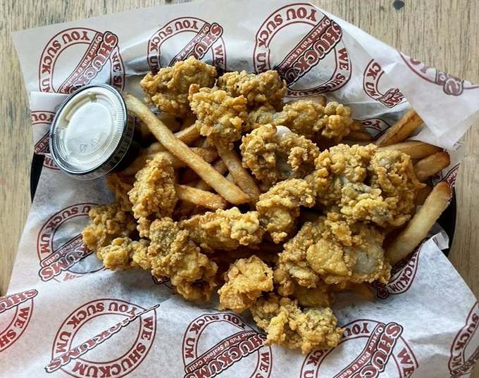 Perfectly golden fried oysters and fries nestled together on branded paper – proof that sometimes the simplest presentations deliver the most satisfaction.