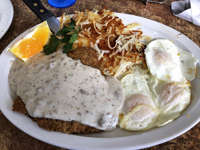 Country fried steak smothered in gravy with eggs on the side—comfort food that hugs your insides like a warm flannel shirt.