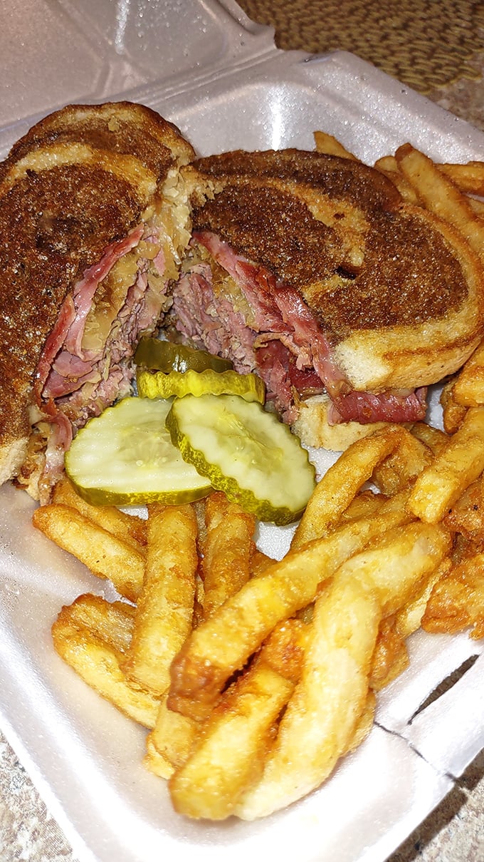 The Reuben—that perfect marriage of corned beef, sauerkraut, and grilled rye—sits proudly alongside crispy fries like it knows exactly how good it is.