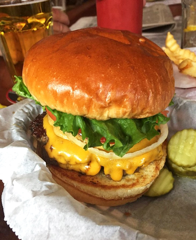 This isn't just a burger—it's an architectural marvel of beef, cheese, and fresh toppings that requires both hands and possibly a strategic eating plan.