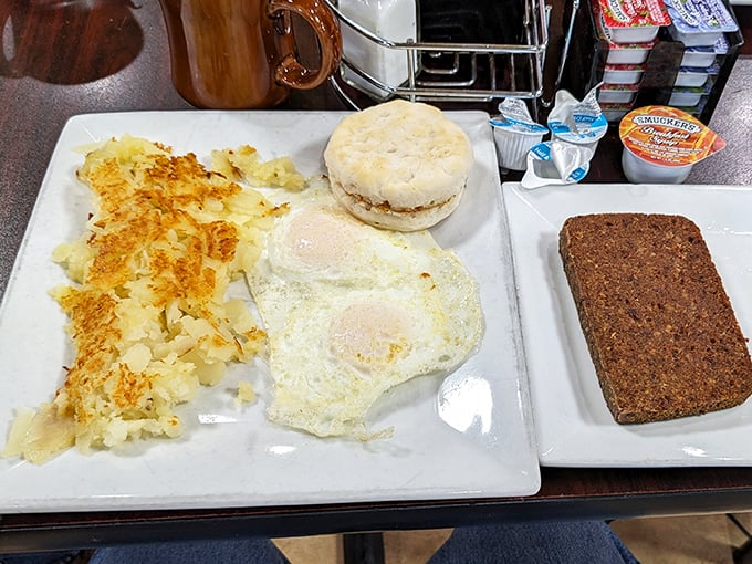 A breakfast that means business: eggs sunny-side up, crispy home fries, a fluffy biscuit, and what appears to be scrapple—Pennsylvania's breakfast of champions.
