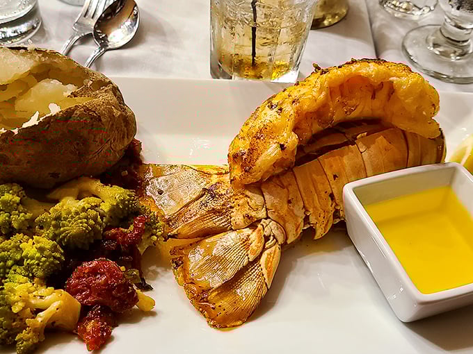 The lobster tail arrives like royalty on a plate, accompanied by a baked potato and colorful vegetables – Neptune's treasure meets landlubber's delight.