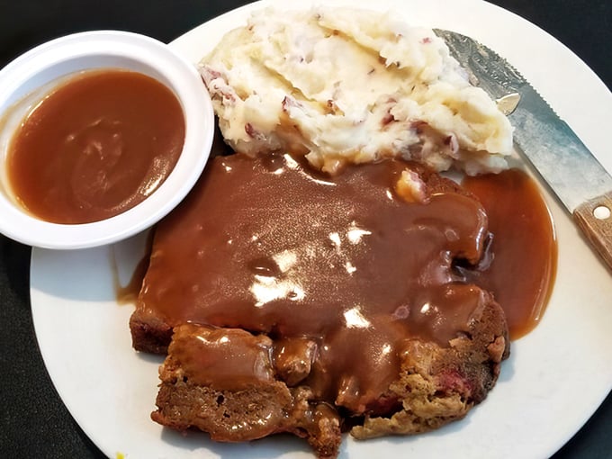 Meatloaf swimming in rich brown gravy alongside red-skinned mashed potatoes—the kind of plate that makes you understand why comfort food earned its name.