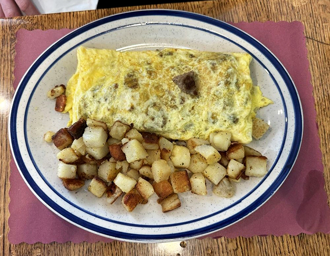 This isn't just an omelet—it's a fluffy yellow canvas of breakfast artistry. The home fries are the supporting actors who steal the scene.