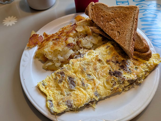 An omelette that knows its purpose in life—delivering melted goodness and hearty fillings with crispy home fries standing guard.