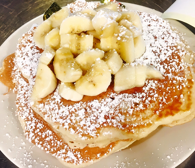 Pancakes crowned with bananas and powdered sugar—the breakfast equivalent of wearing a tiara to start your day right.