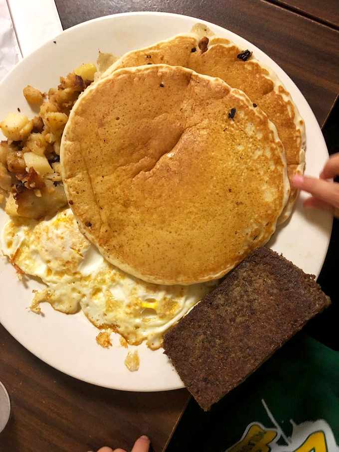 These pancakes aren't just big—they're life-affirming. Golden discs of joy that hang over the plate's edge like delicious solar eclipses.