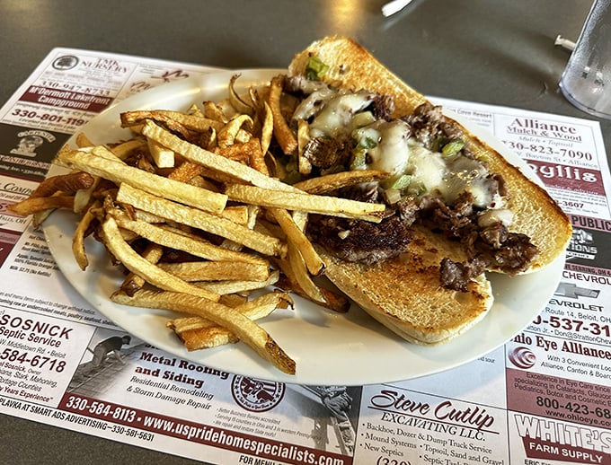 A proper Philly cheesesteak that doesn't need Philadelphia's permission—melty cheese cascading over savory beef with perfectly crisp fries standing guard.