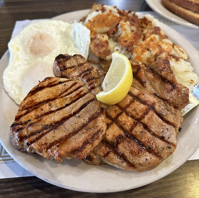 A pork chop with grill marks so perfect they could be framed in a museum. The sunny-side egg stands by, ready to create the sauce nature intended.