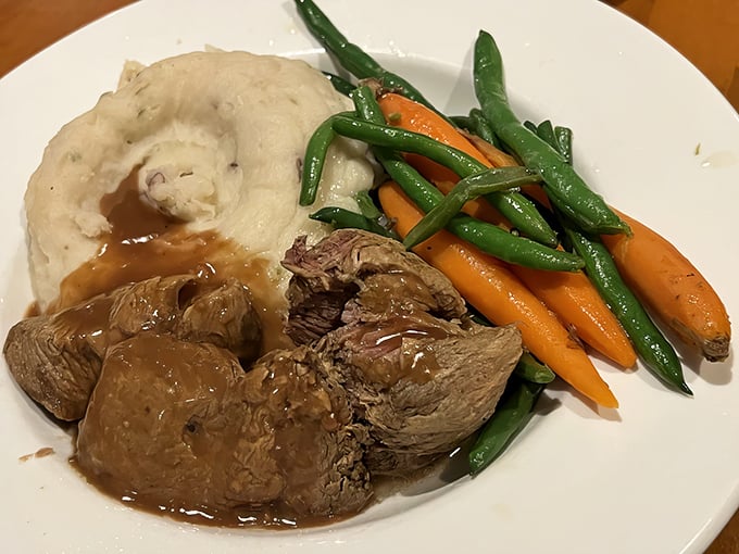 Comfort on a plate: tender pot roast swimming in savory gravy alongside mashed potatoes and vegetables. Grandma would approve, then ask for the recipe.