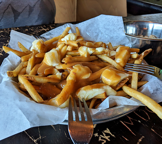 Poutine gets the Wisconsin treatment at AJ Bombers—crispy fries drowning under a blanket of cheese sauce that would make a Canadian simultaneously weep and applaud.