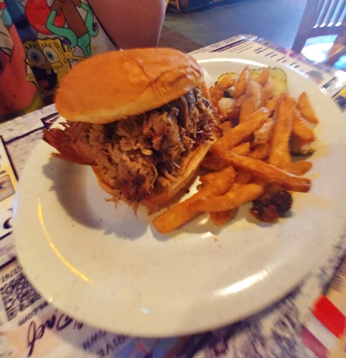 This pulled pork sandwich isn't just a meal, it's architectural achievement—towering with tender meat that's been introduced to smoke and time.