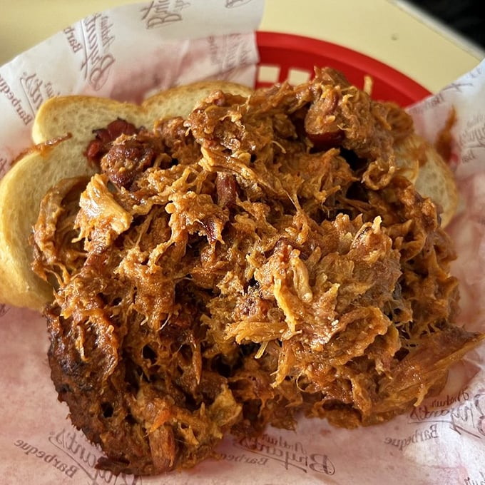 A mountain of pulled pork that's been coaxed into tender submission, piled high on white bread—simplicity that speaks volumes about barbecue philosophy. 