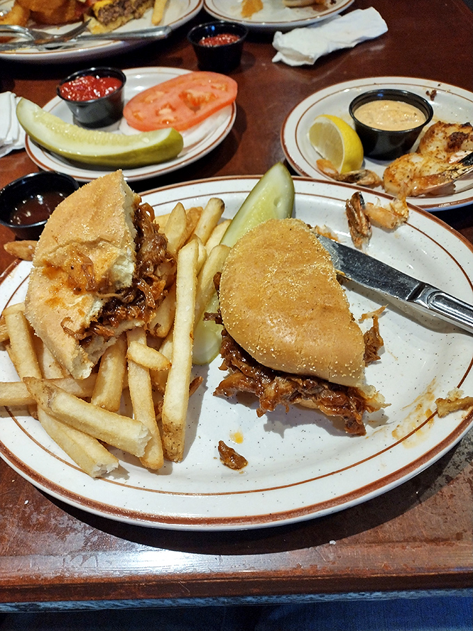 The pulled pork sandwich arrives with golden fries—a handheld masterpiece that proves simplicity and smoke make the perfect marriage.