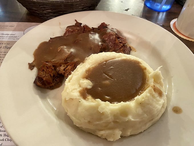 Mashed potatoes sculpted into a gravy volcano alongside tender roast beef—comfort food engineering at its finest.