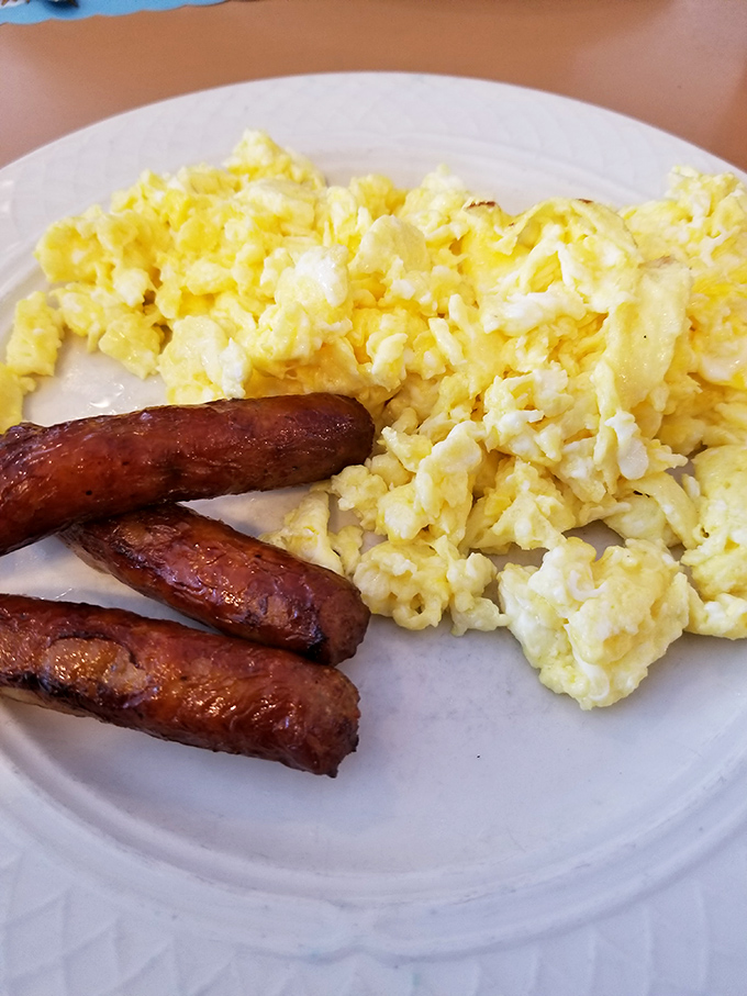 Scrambled eggs that actually taste like eggs—fluffy, buttery clouds alongside sausage links that snap with each bite.