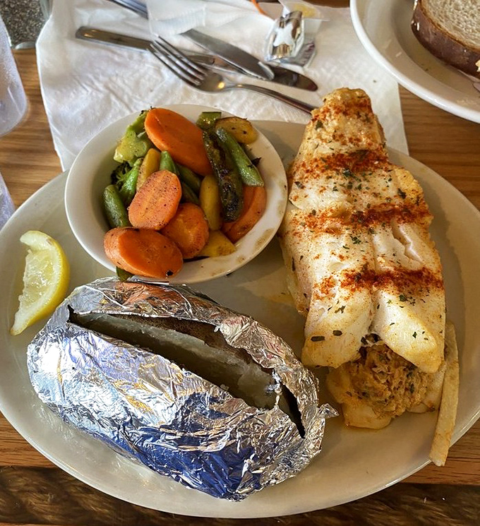 A plate that whispers "vacation" – perfectly grilled fish alongside vibrant vegetables and a foil-wrapped potato hiding its buttery secrets.