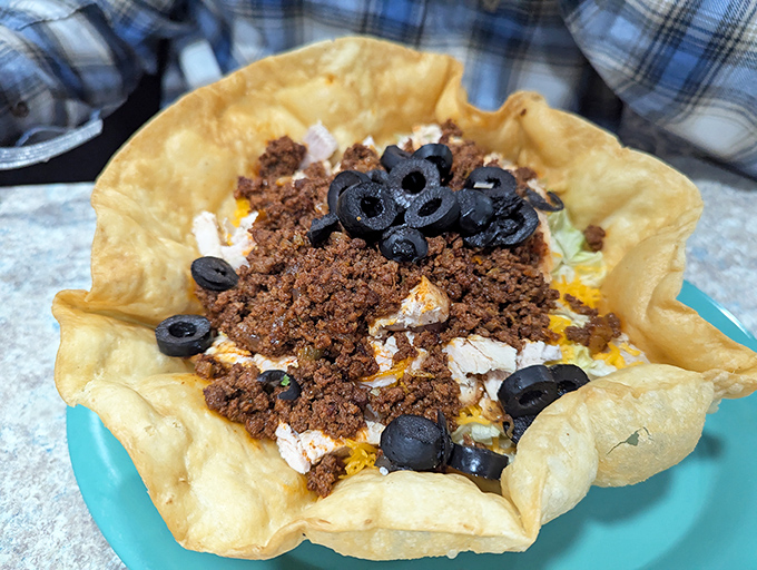 This taco salad isn't just wearing an edible bowl—it's sporting a party hat of seasoned beef, cheese, and olives that says "fiesta on a plate."