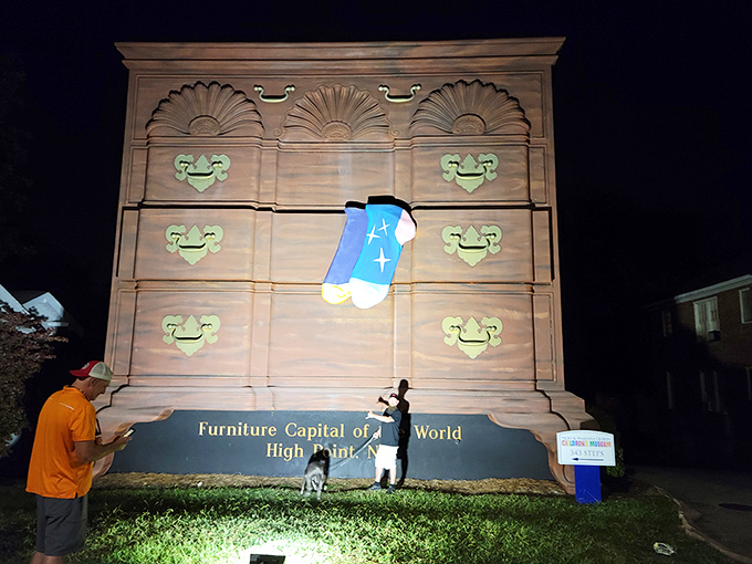 Nighttime transforms the giant dresser into a glowing beacon of quirky charm, drawing visitors and their four-legged friends for evening selfies.