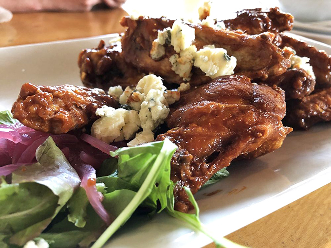 These aren't just wings—they're crispy, sauce-lacquered flavor bombs topped with crumbled blue cheese that make sharing an act of true friendship.