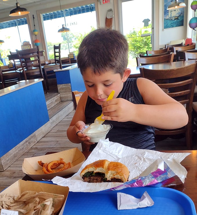 The burger arrives wearing its cheese like a well-earned medal, with onion rings standing guard—a plate that says "vacation" louder than your Hawaiian shirt.