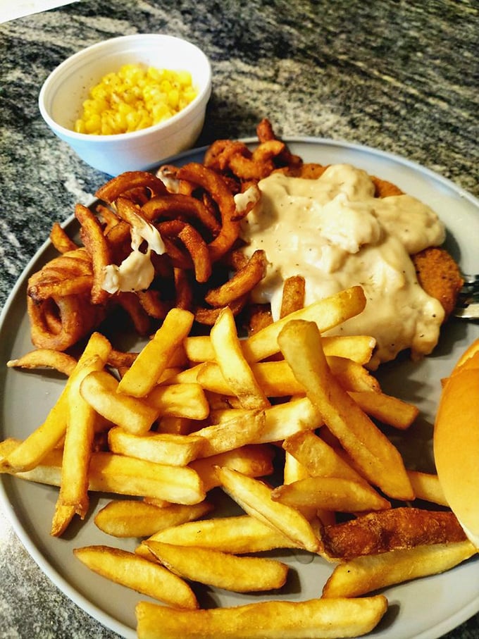 Country fried goodness smothered in creamy gravy with golden fries and onion rings standing by. This plate doesn't just feed you – it hugs you from the inside.