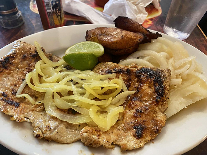 Grilled chicken with sautéed onions and a lime wedge—proof that simplicity, when done right, can outshine complexity every time.
