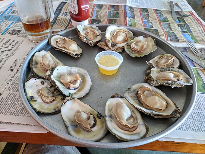 These oysters aren't just served—they're presented with the reverence of crown jewels, glistening on their metal throne with a humble cup of sauce.