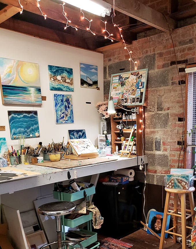 An artist's corner where creativity flows – ocean-inspired paintings and well-worn brushes hint at the artistic community thriving within these brick walls. 