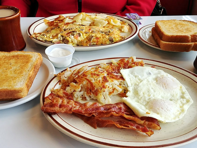 Breakfast perfection on a plate—crispy bacon, eggs with sunshine-yellow yolks, and hash browns that crackle with each forkful.